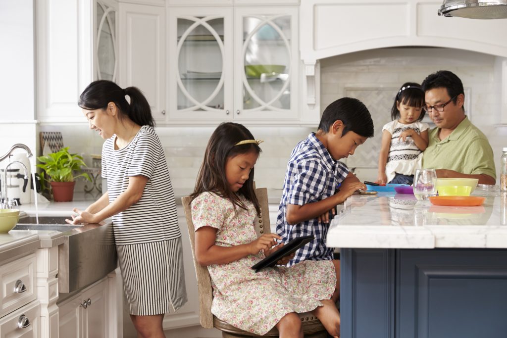 Family In Kitchen Doing Chores And Using Digital Devices - Sensory ...
